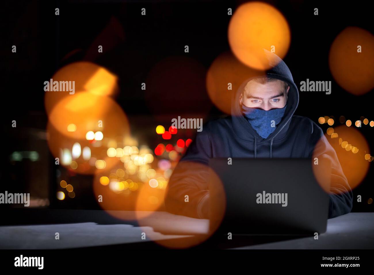 Young talented hacker using laptop computer while working in dark ...