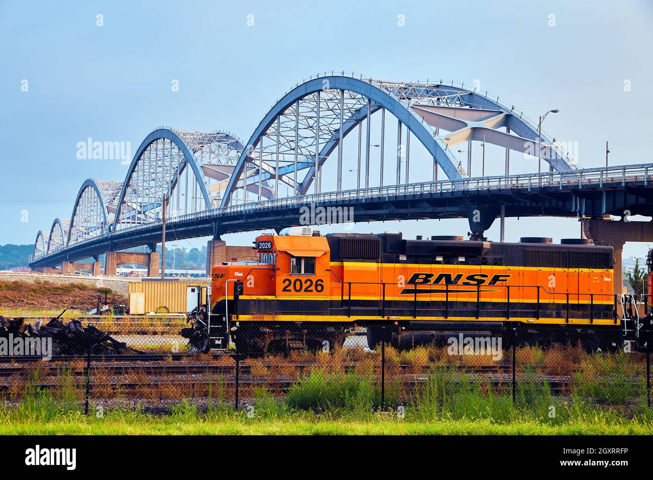 Train on tracks with large bridge in background Stock Photo - Alamy