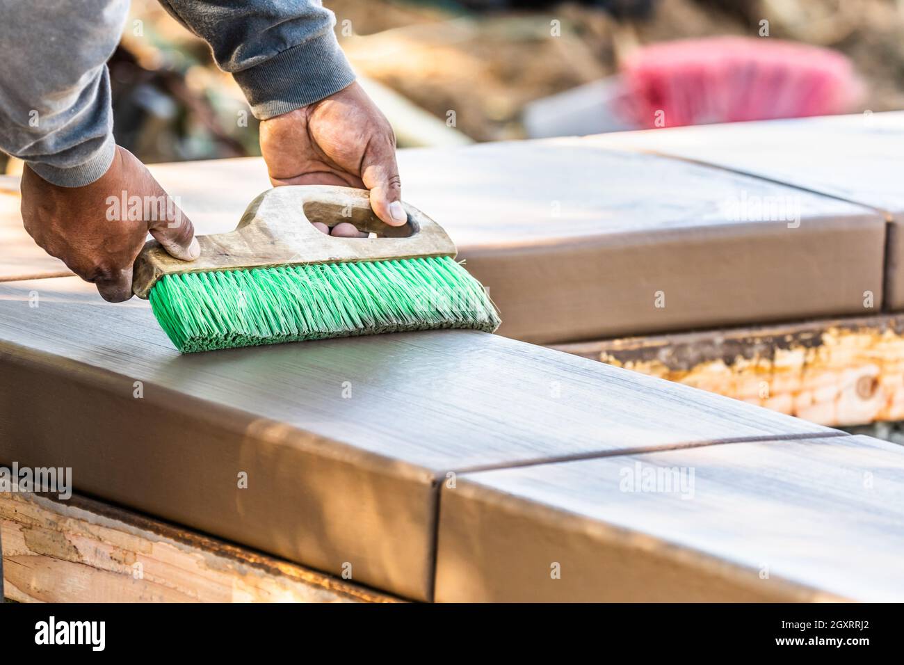 Construction Worker Using Brush On Wet Cement Forming Coping Around New ...