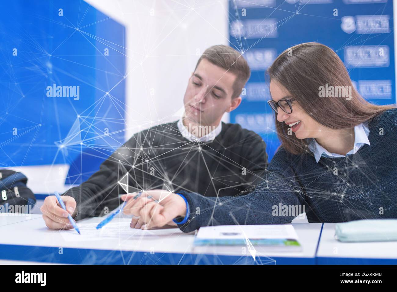 Two young students man and woman with others working on a project in a ...