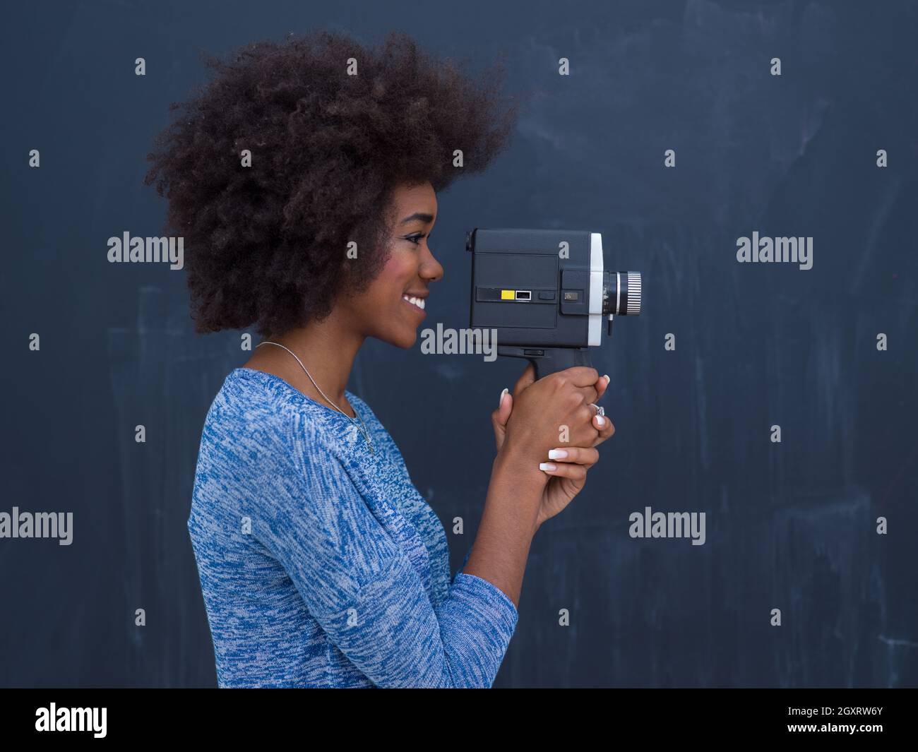 A young beautiful african american woman using a retro video camera ...