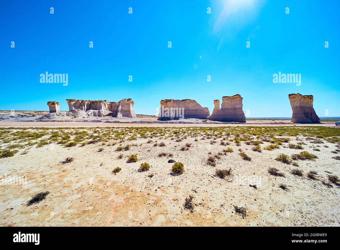 Flat desert landscape with dirt road and unusual pillars of white rock ...