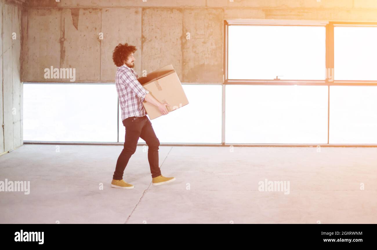 happy young casual business man carrying cardboard box with sunlight ...