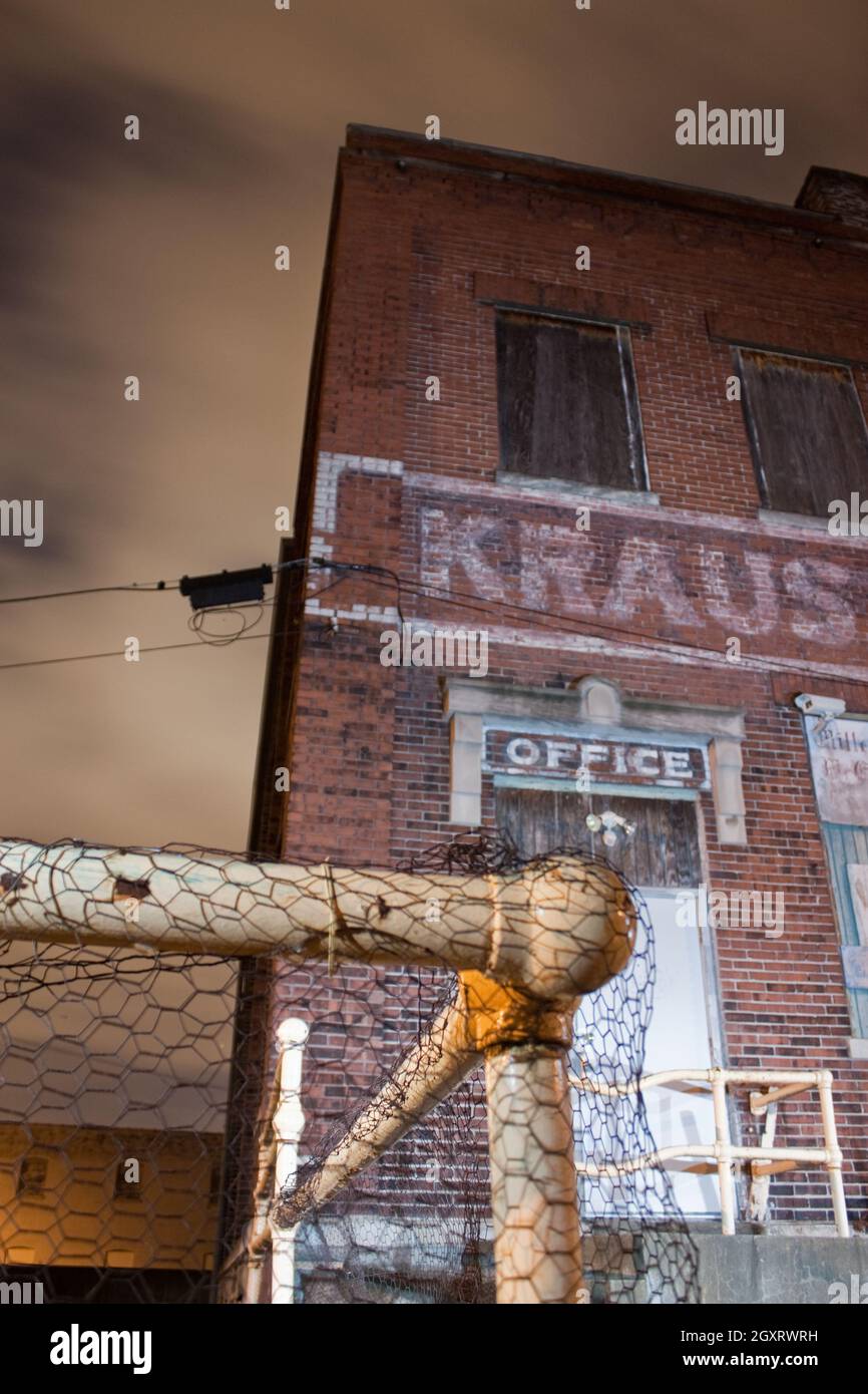 Old brick building with chicken wire fence in front lit by lamplight ...