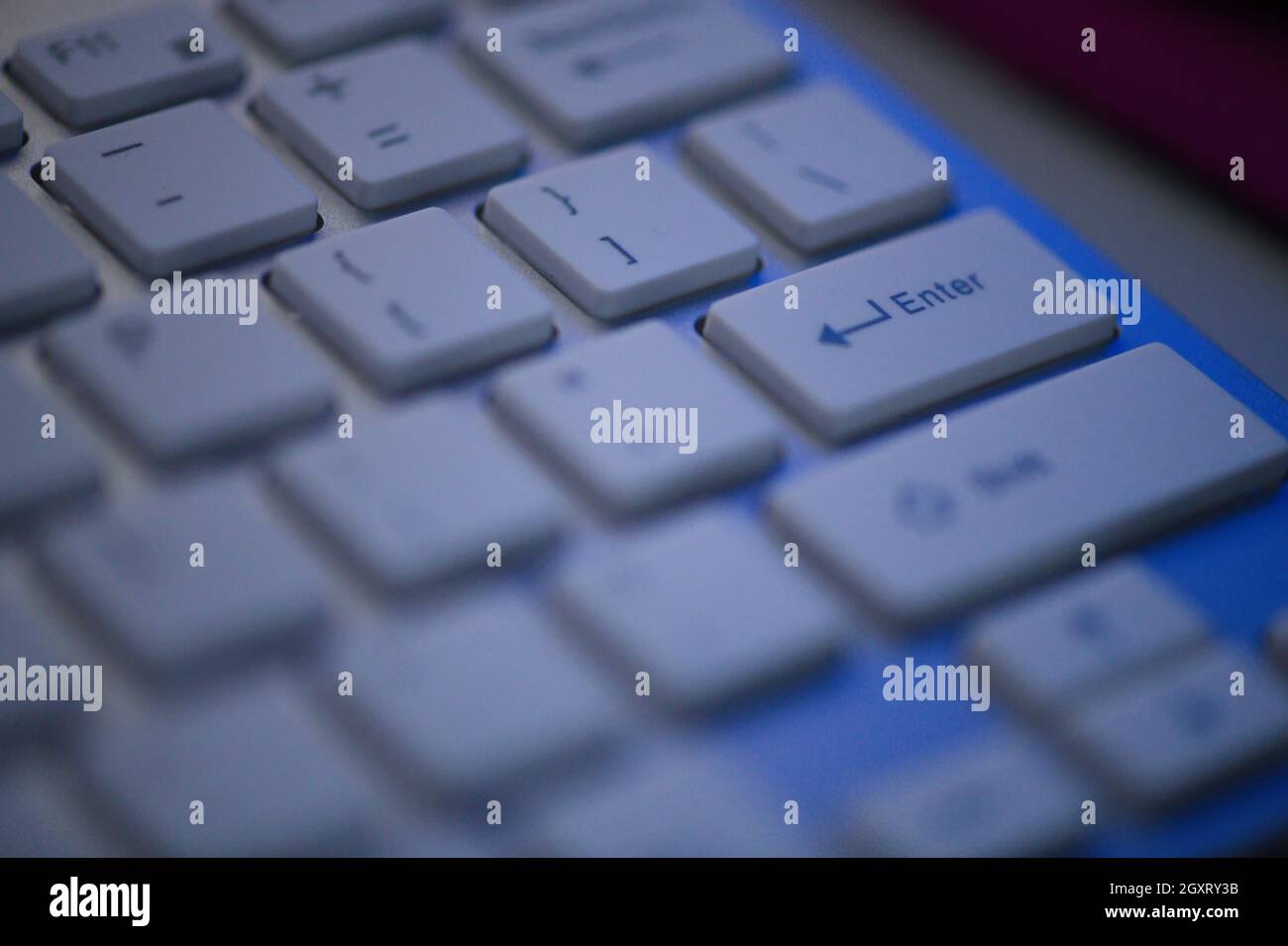 slim white minimalistic keyboard close up in dark night lit by screen ...