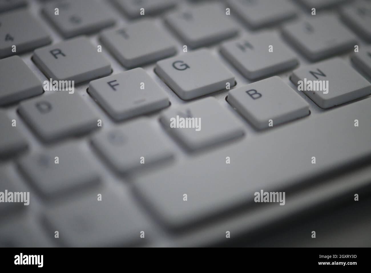 slim white minimalistic keyboard close up in dark night lit by screen ...