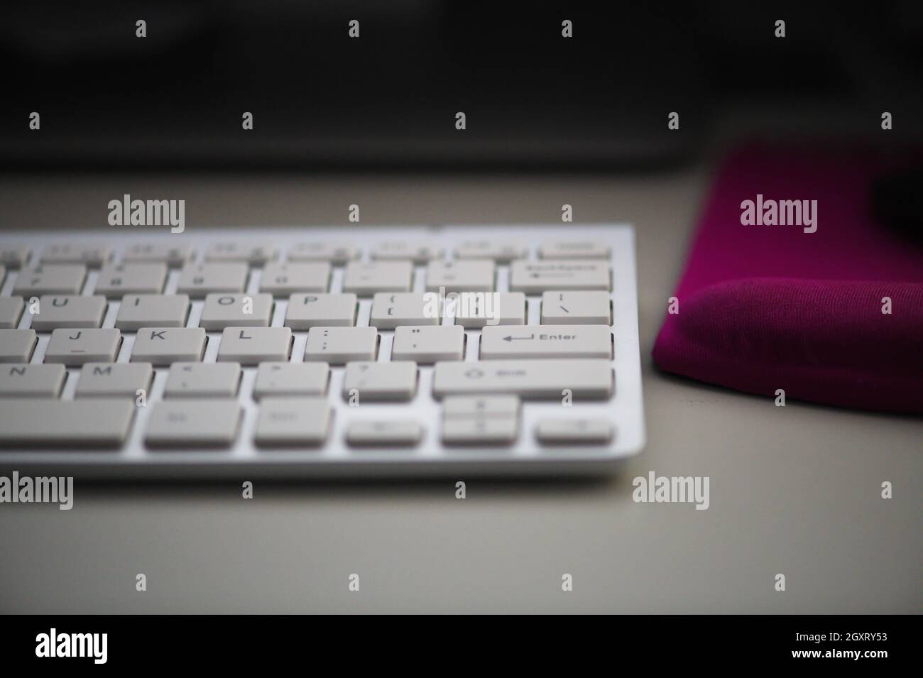 slim white minimalistic keyboard close up in dark night lit by screen ...