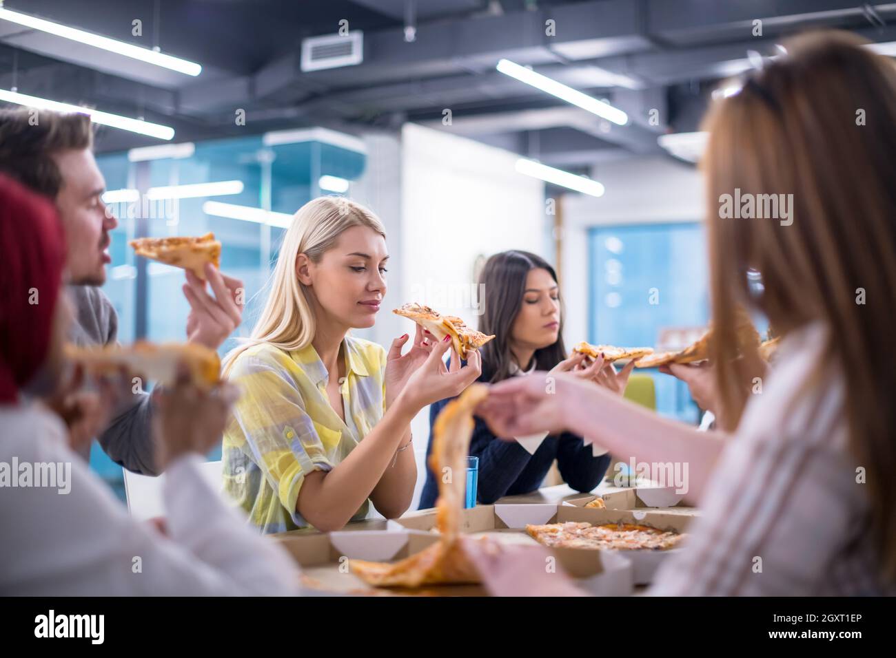 Friendly diverse multiethnic business team eating sharing pizza together in startup office ...