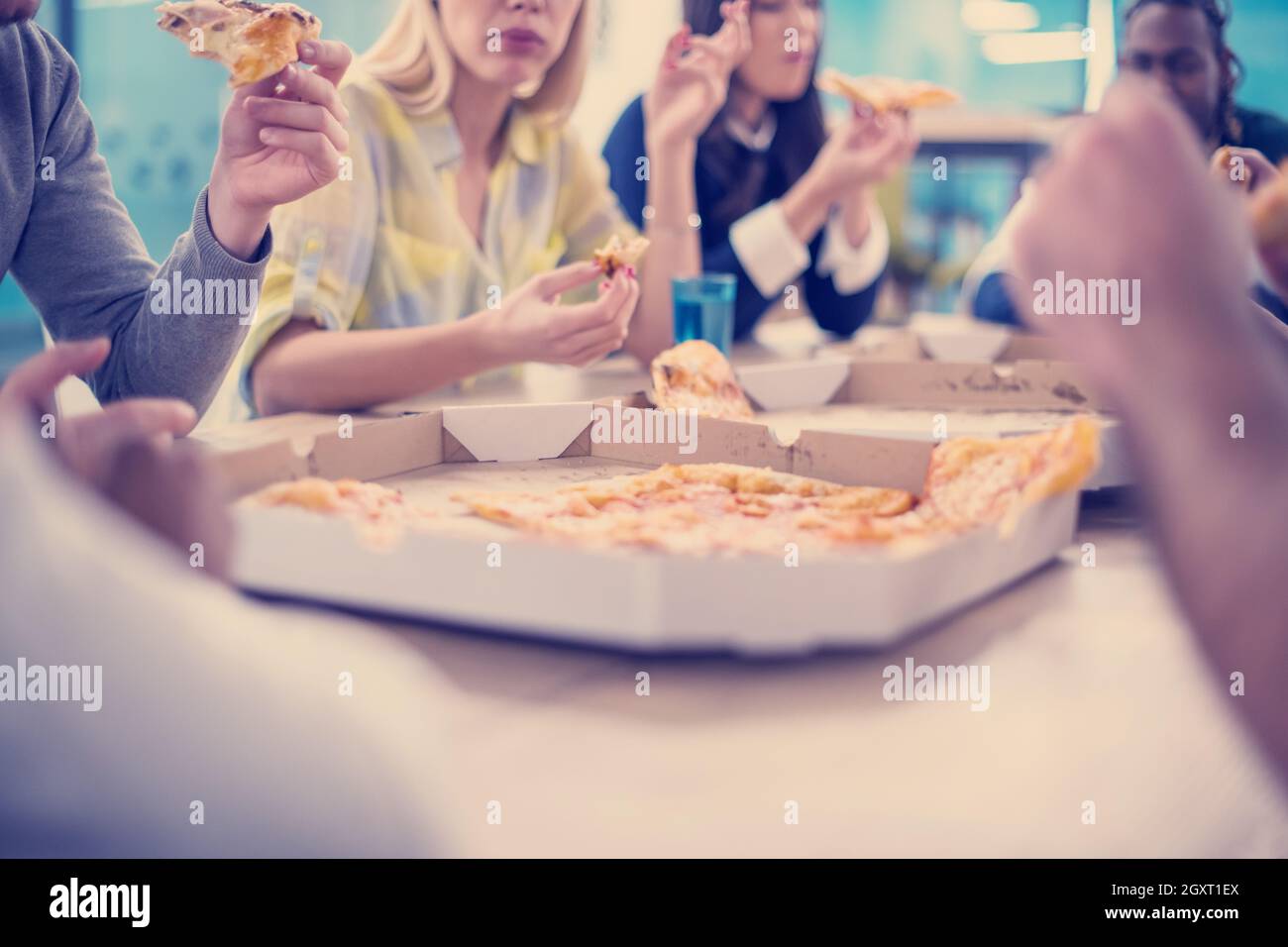 Friendly diverse multiethnic business team eating sharing pizza together in startup office ...
