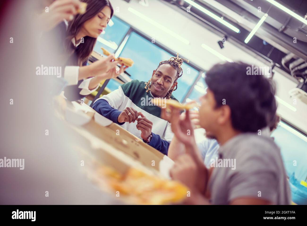 Friendly diverse multiethnic business team eating sharing pizza together in startup office ...