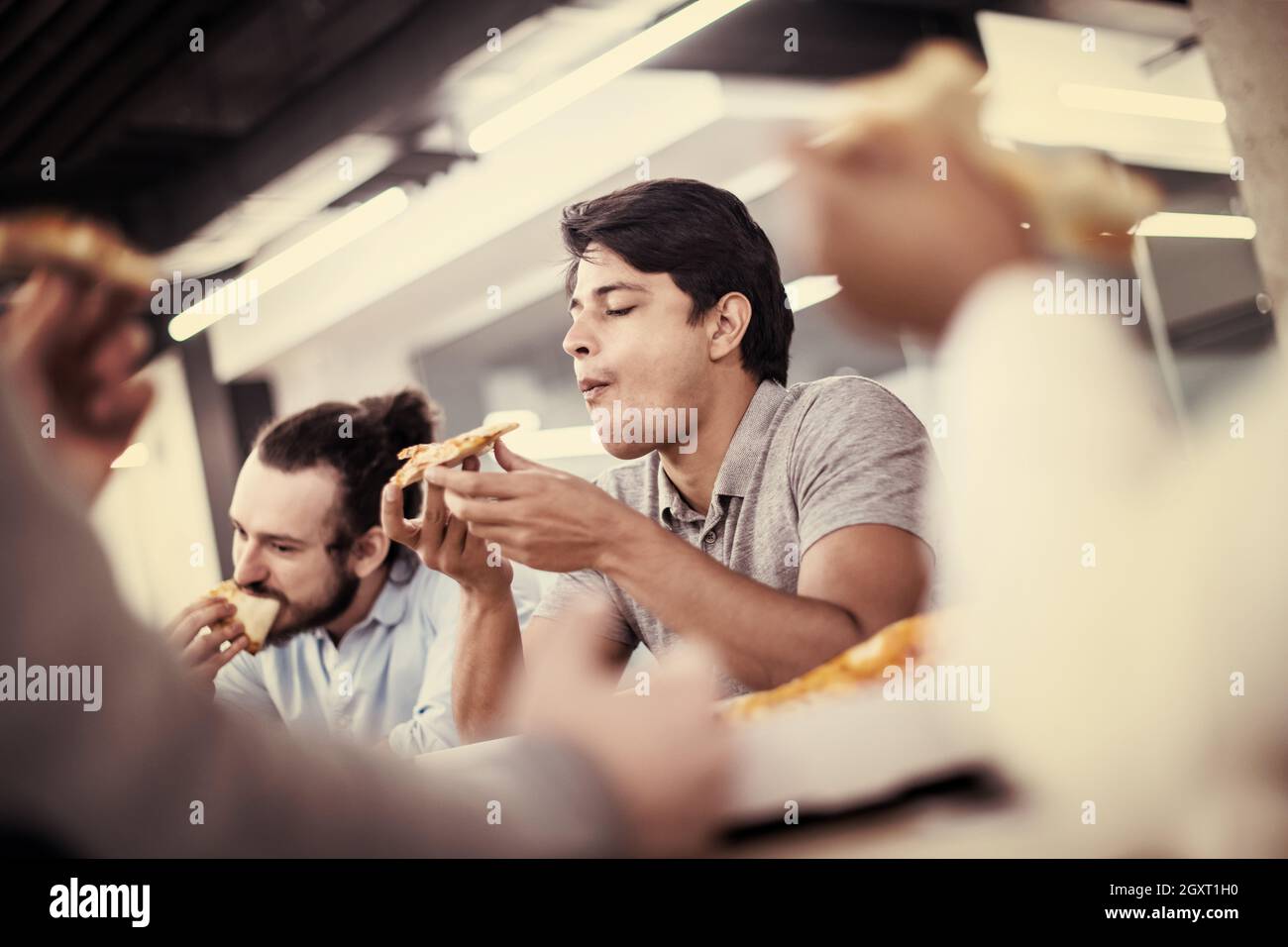 Friendly diverse multiethnic business team eating sharing pizza together in startup office ...