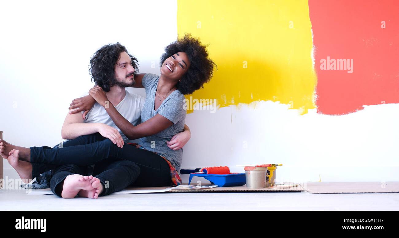 Happy young multiethnic couple relaxing after painting a room in their ...
