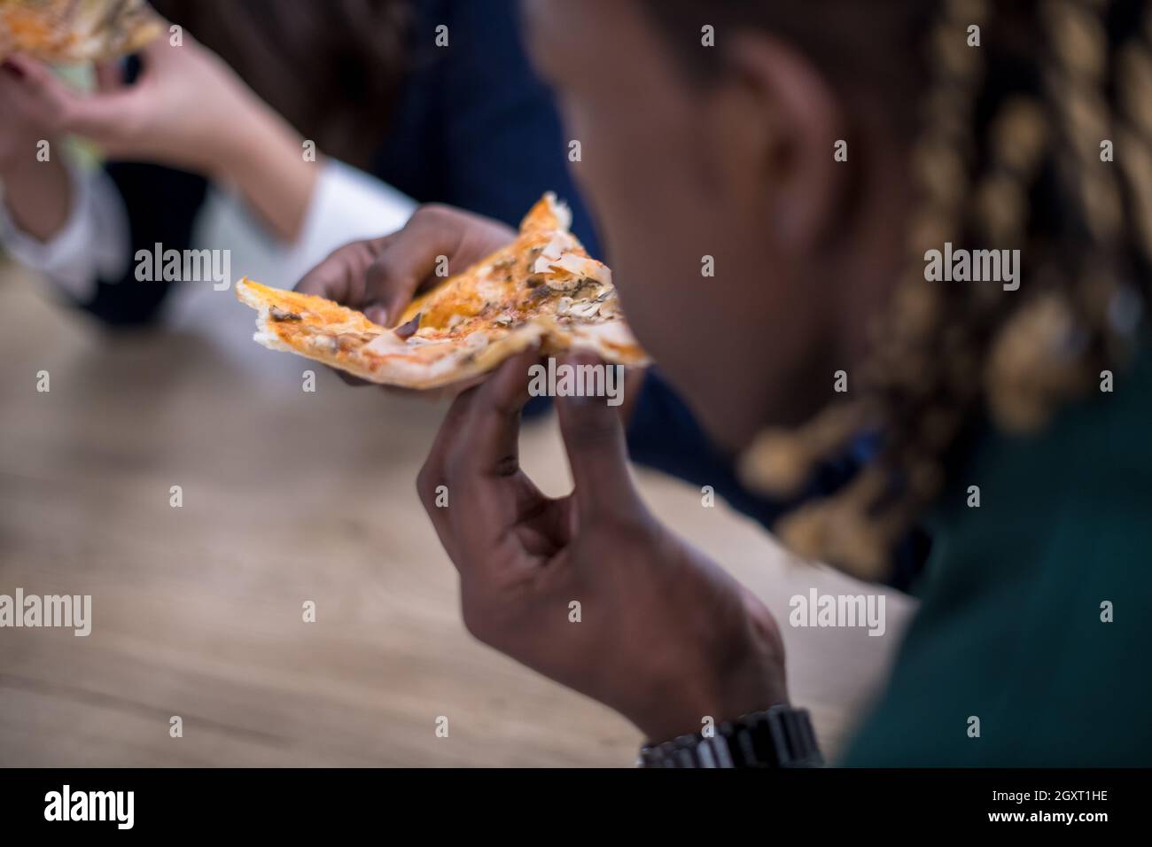 Friendly diverse multiethnic business team eating sharing pizza together in startup office ...