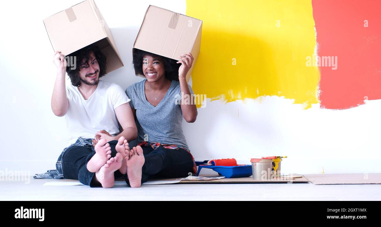 Happy young multiethnic couple relaxing and playing with cardboard ...