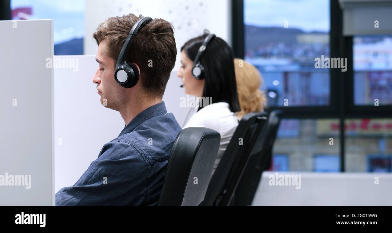 young smiling male call centre operator doing his job with a headset ...