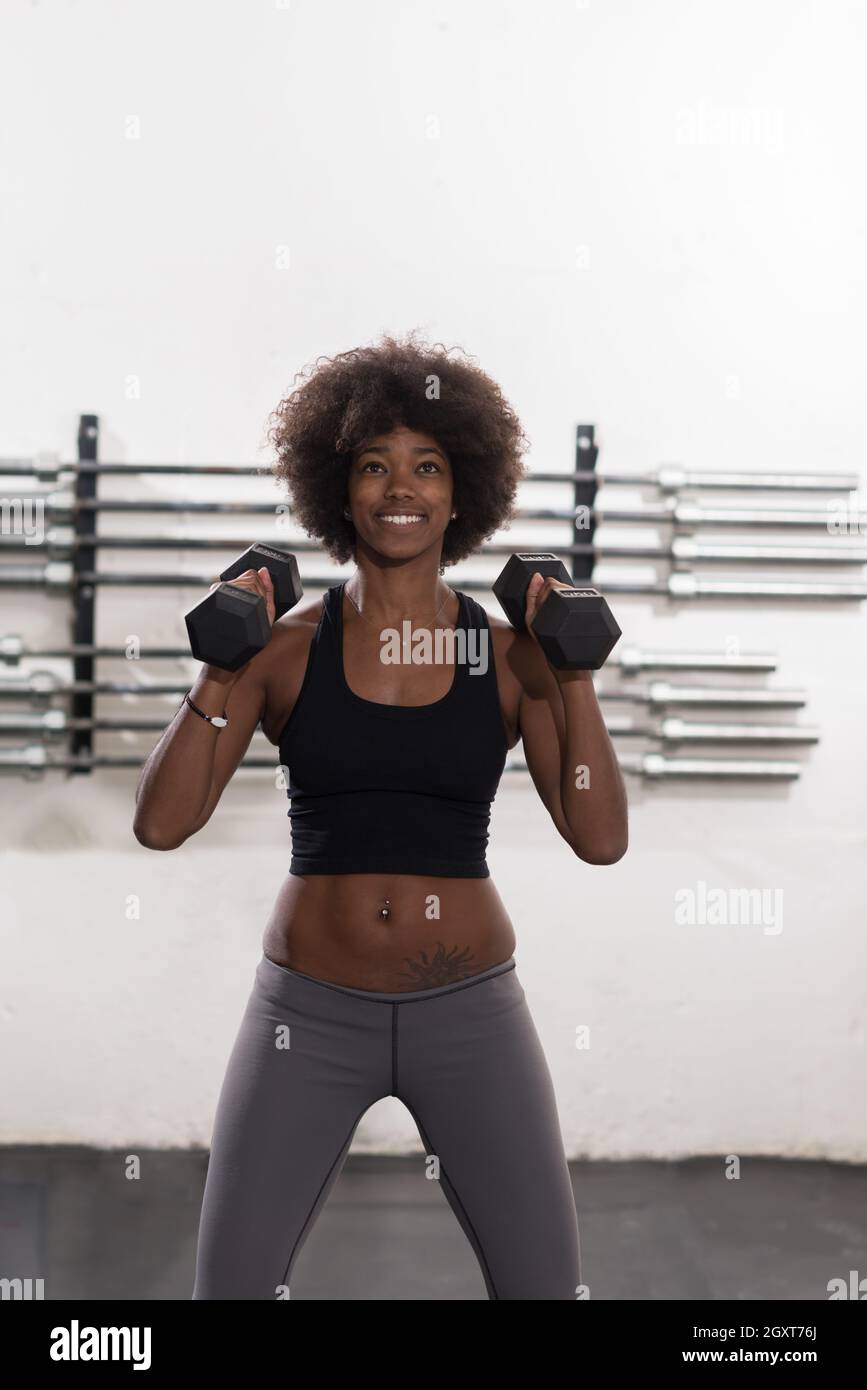 Woman doing bicep curls with dumbbells at a gym hi-res stock ...