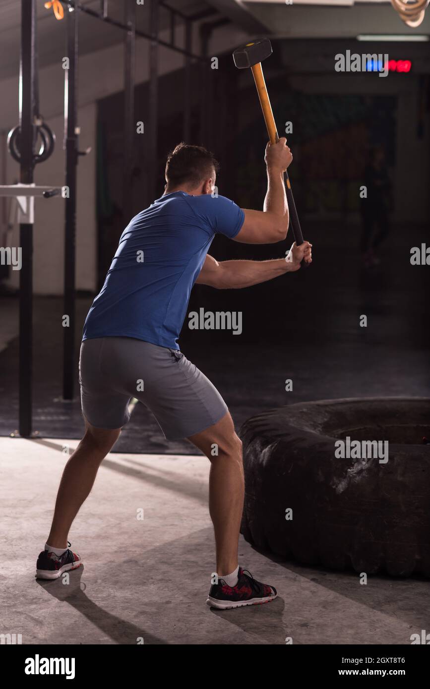 Sledgehammer Tire Hits young muscular man workout at gym with hammer ...