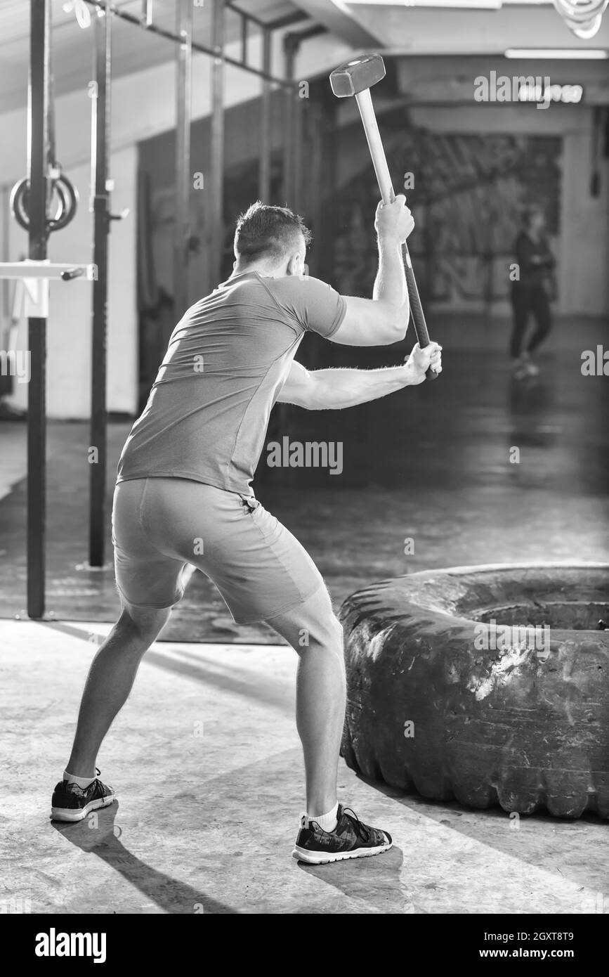 Sledgehammer Tire Hits young muscular man workout at gym with hammer ...