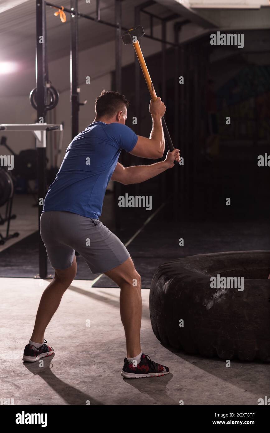 Sledgehammer Tire Hits young muscular man workout at gym with hammer ...