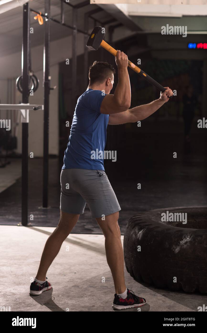 Sledgehammer Tire Hits young muscular man workout at gym with hammer ...