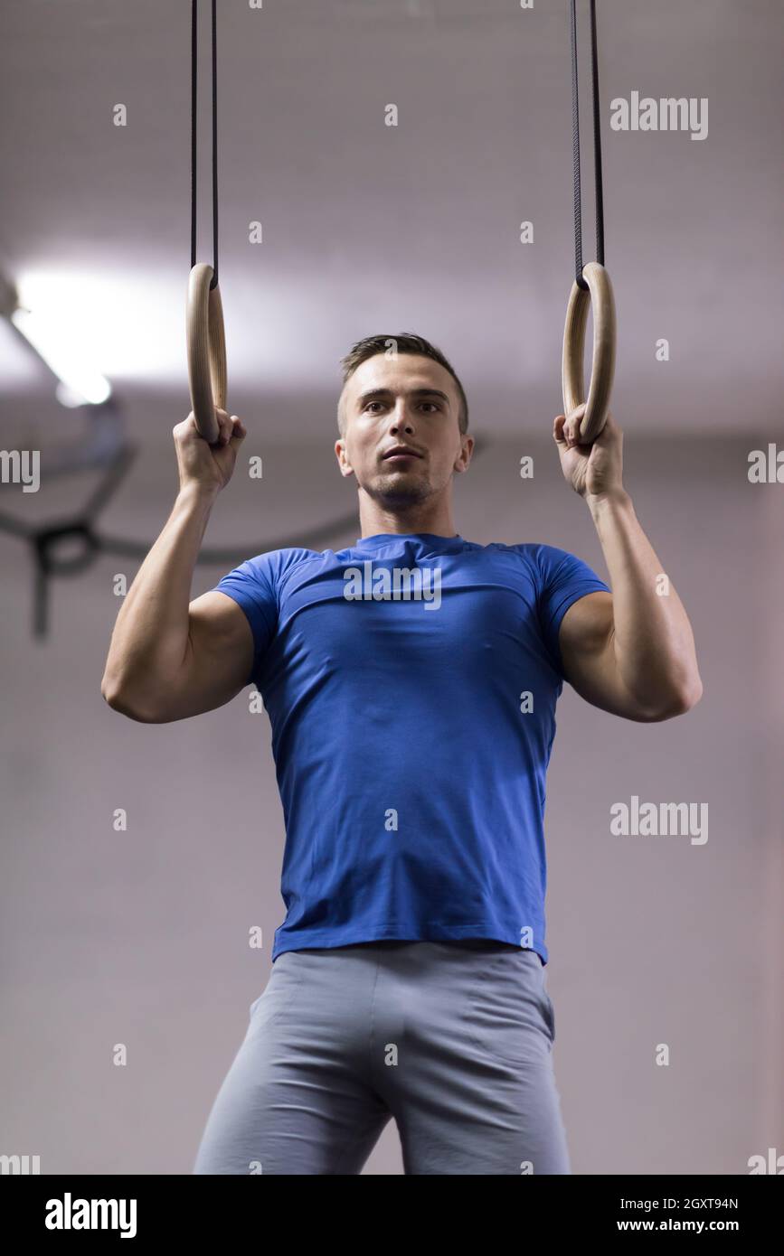 Fitness handsome man doing dipping exercise using rings in the gym ...
