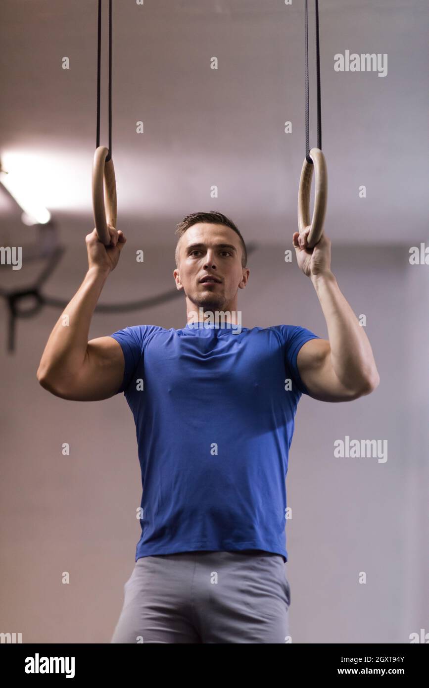 Fitness handsome man doing dipping exercise using rings in the gym ...