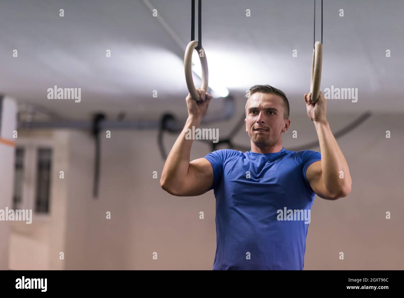 Fitness handsome man doing dipping exercise using rings in the gym ...