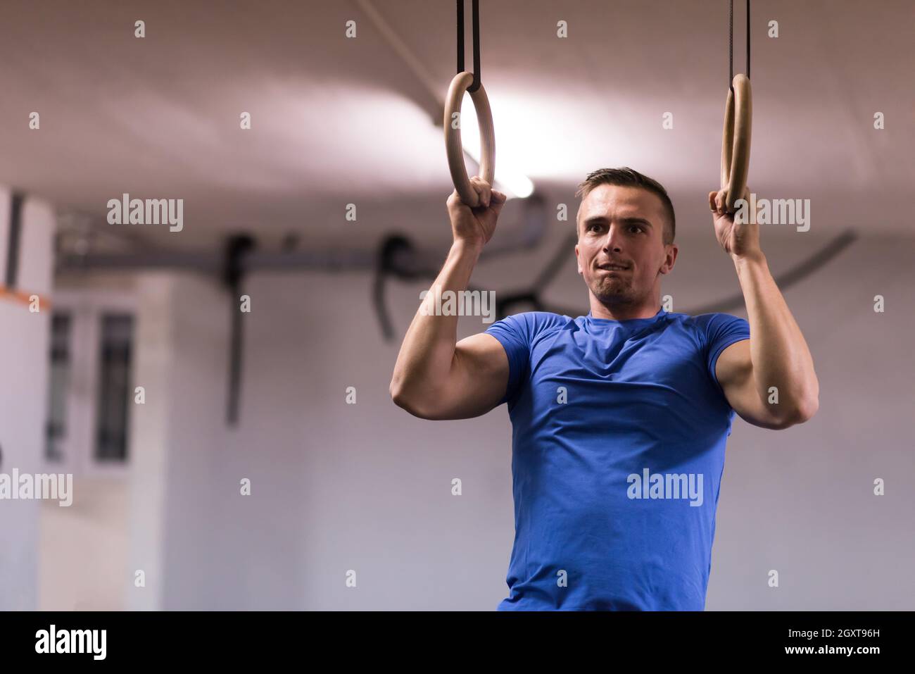 Fitness handsome man doing dipping exercise using rings in the gym ...