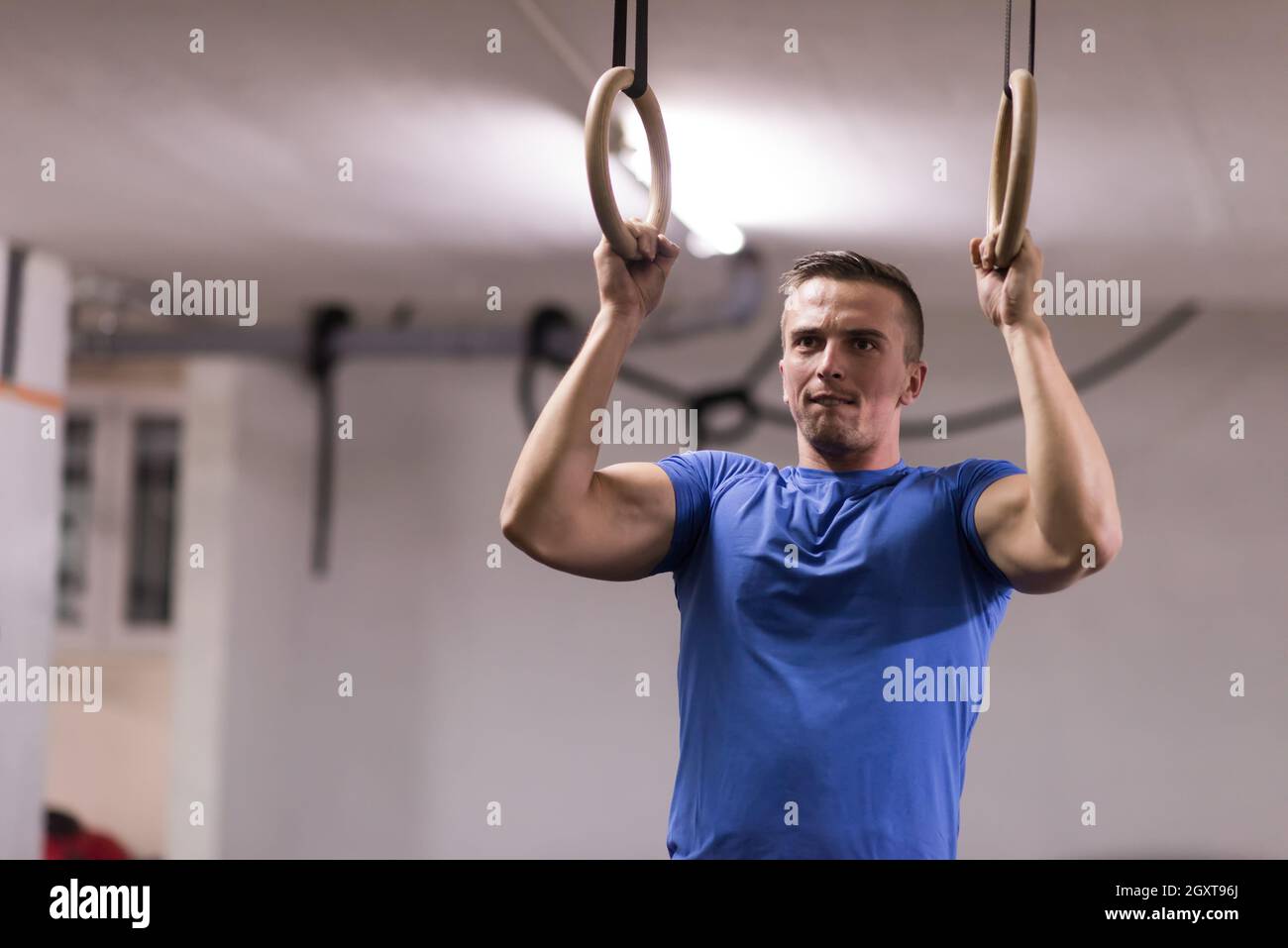 Fitness handsome man doing dipping exercise using rings in the gym ...