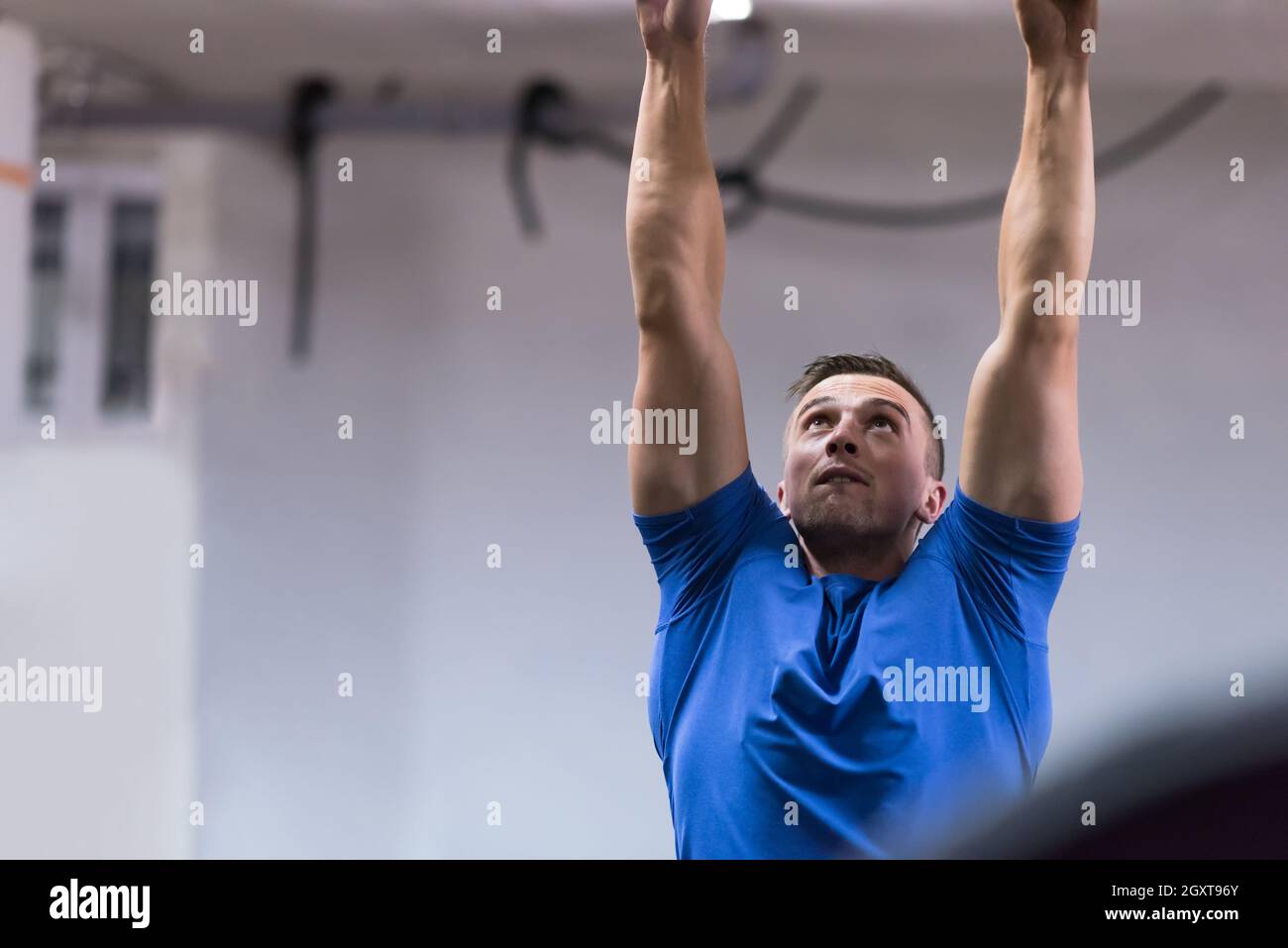 Fitness handsome man doing dipping exercise using rings in the gym ...