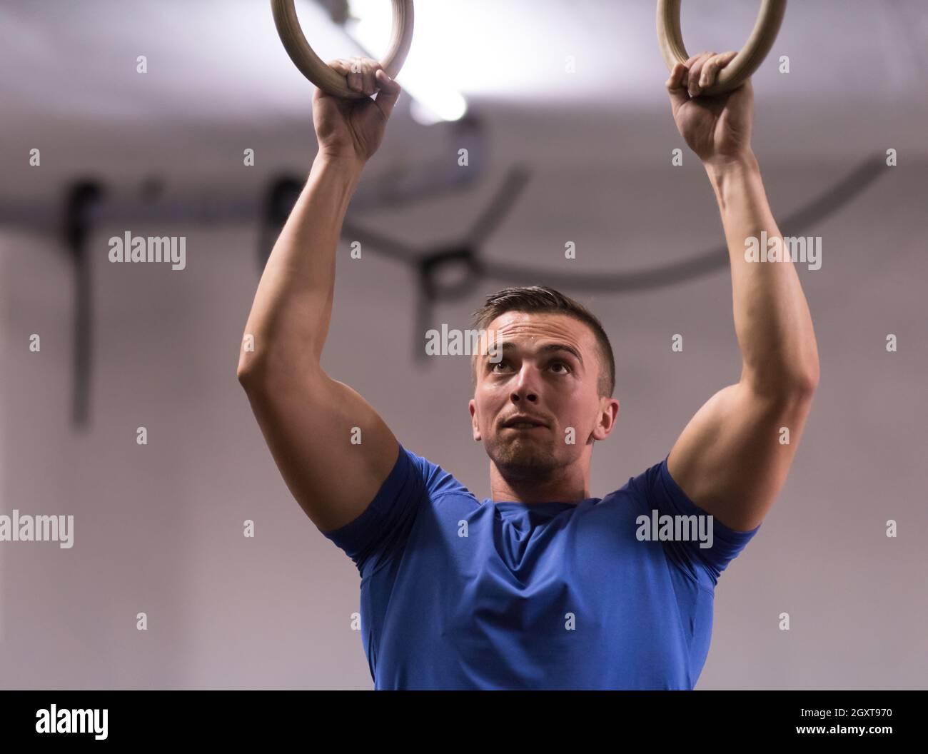 Fitness handsome man doing dipping exercise using rings in the gym ...