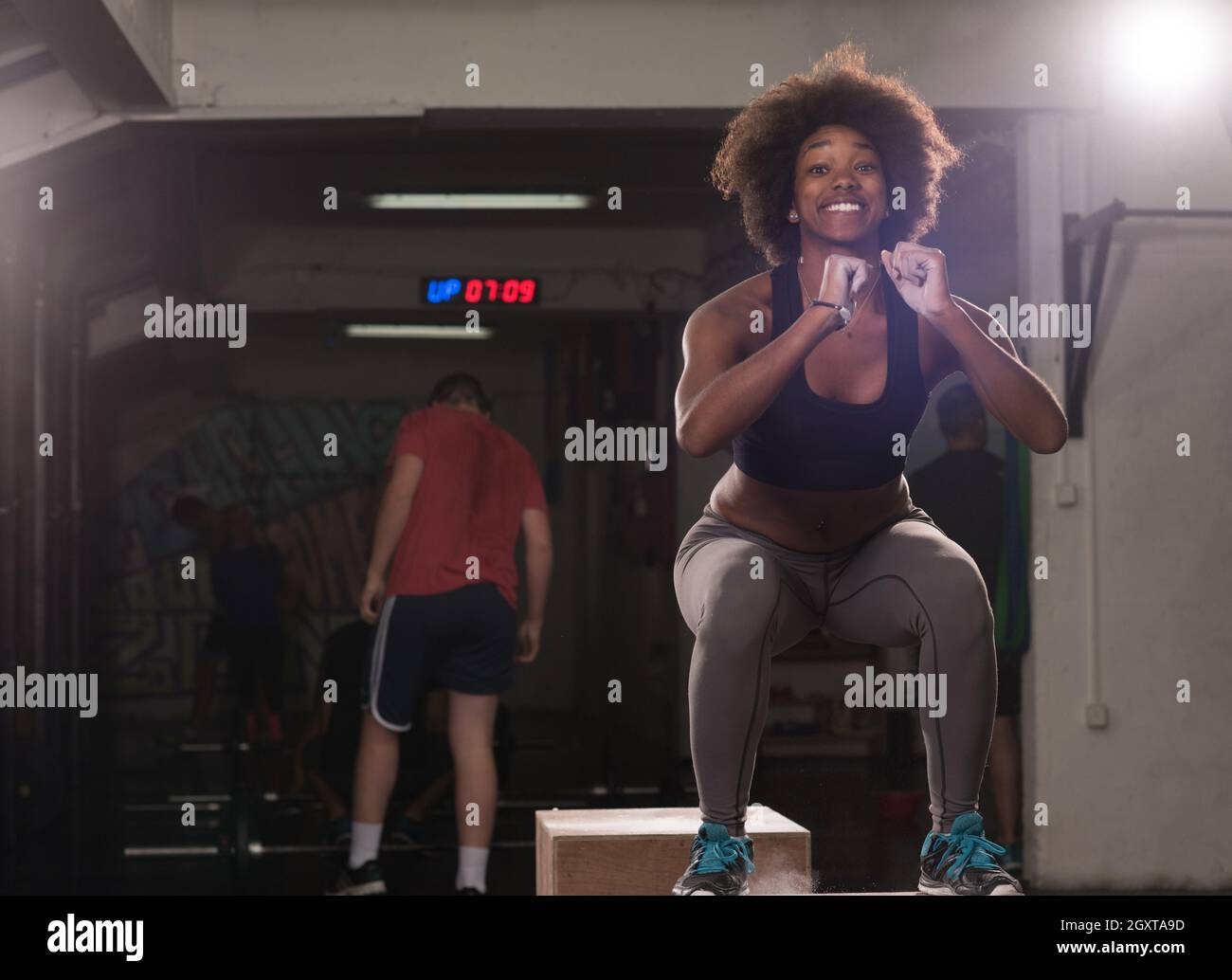 Fit young african american woman box jumping at a crossfit style gym ...