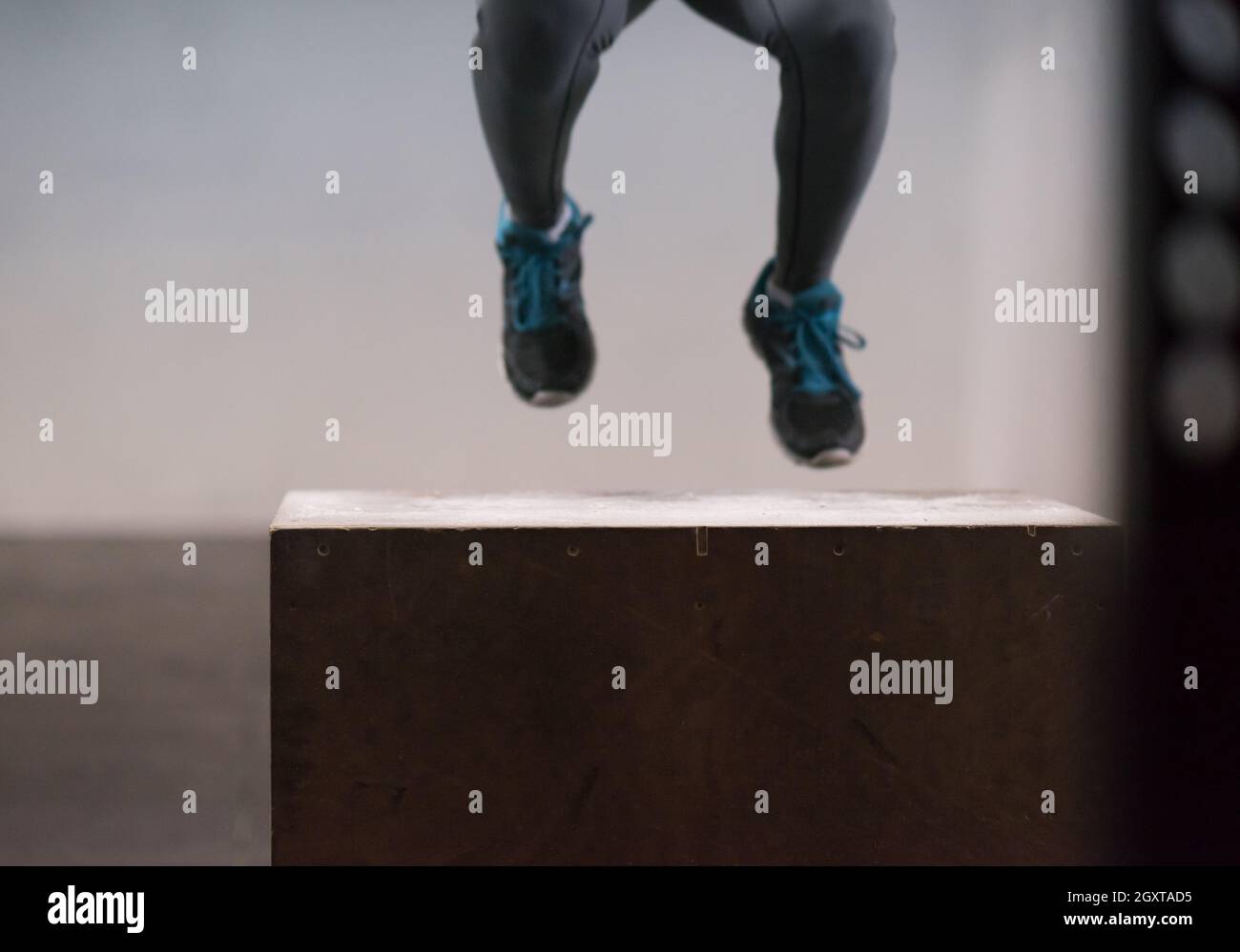 Fit young african american woman box jumping at a crossfit style gym ...