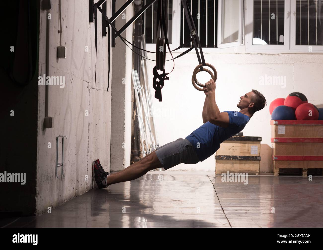 Fitness handsome man doing dipping exercise using rings in the gym ...