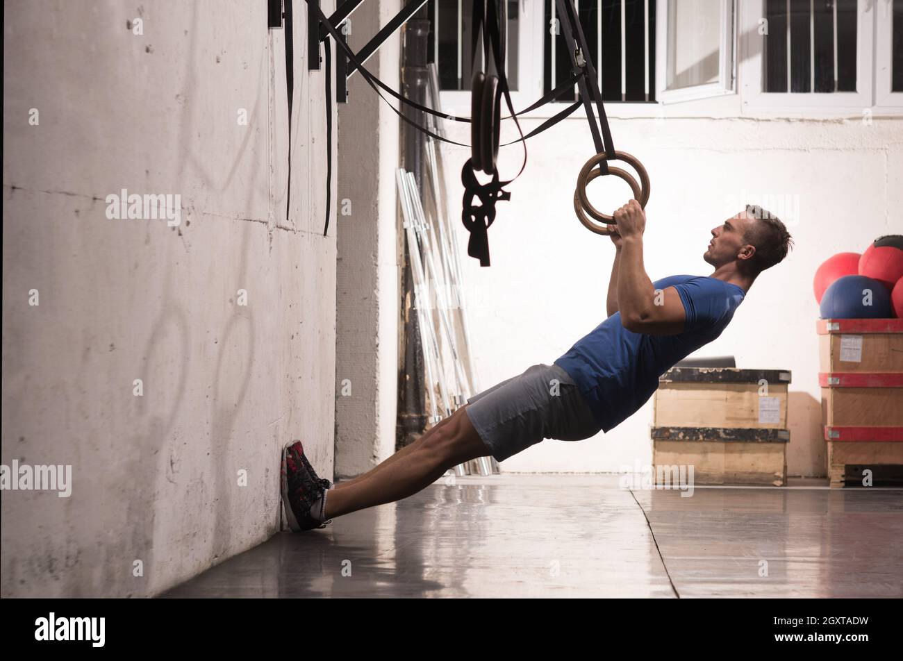 Fitness handsome man doing dipping exercise using rings in the gym ...