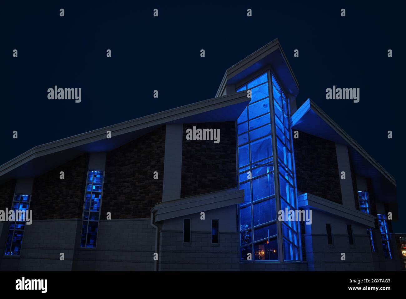 Large windowed chapel exterior lit blue at night Stock Photo - Alamy