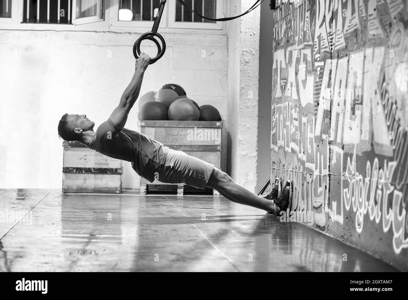 Fitness handsome man doing dipping exercise using rings in the gym ...