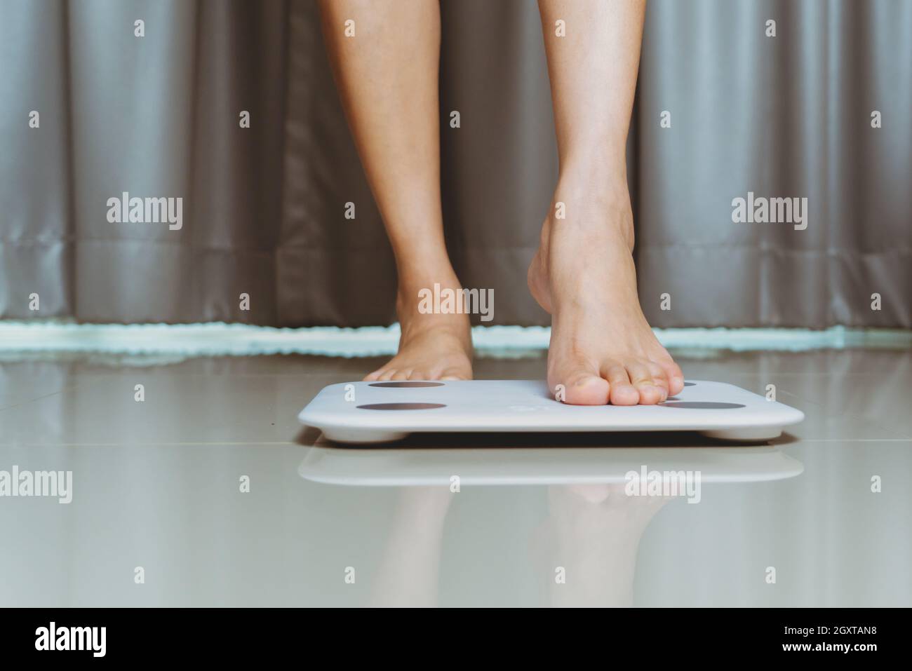 Female leg is stepping on white scales at home Stock Photo - Alamy