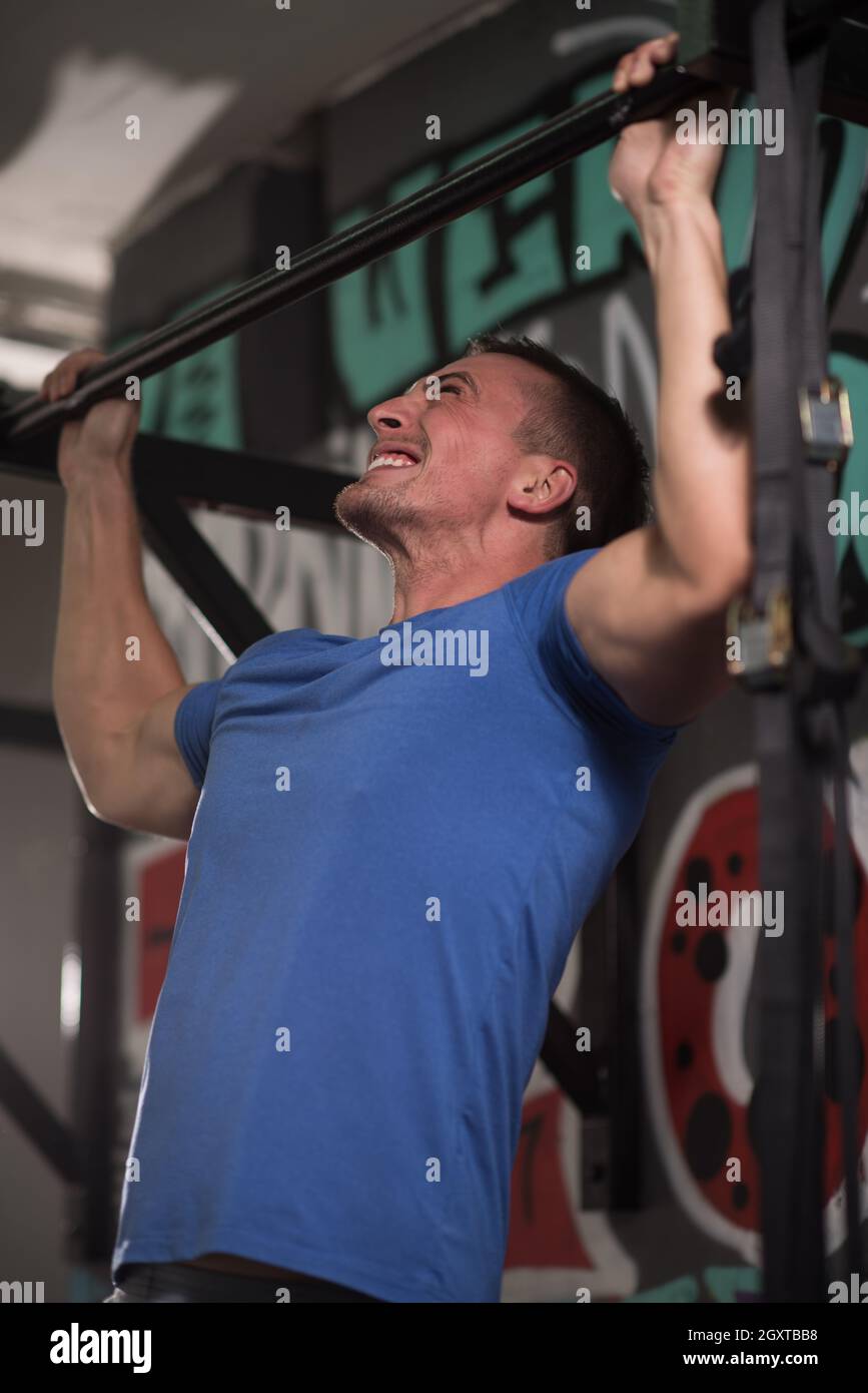strong young man doing pull ups on a bar in a gym Stock Photo - Alamy
