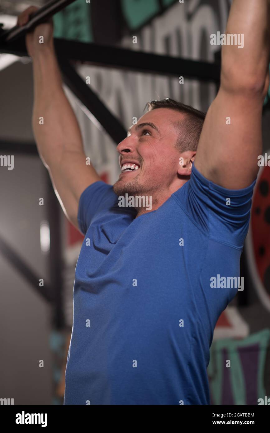 strong young man doing pull ups on a bar in a gym Stock Photo - Alamy