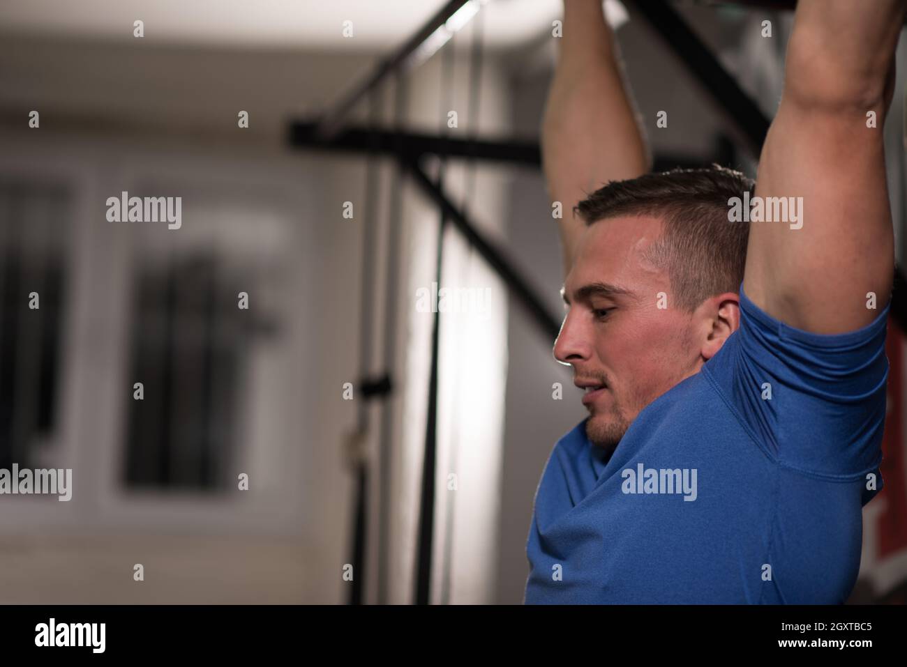 strong young man doing pull ups on a bar in a gym Stock Photo - Alamy