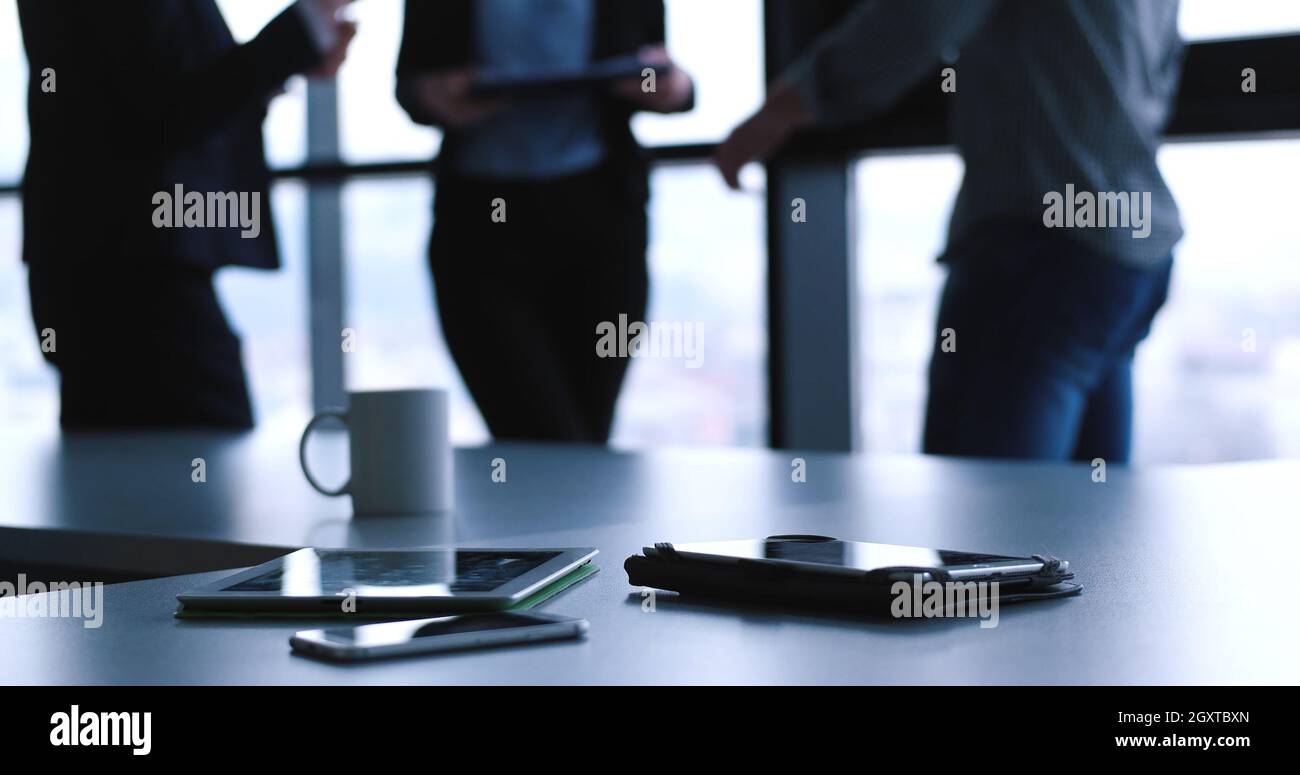 Devices on table with business people in background in modern office ...