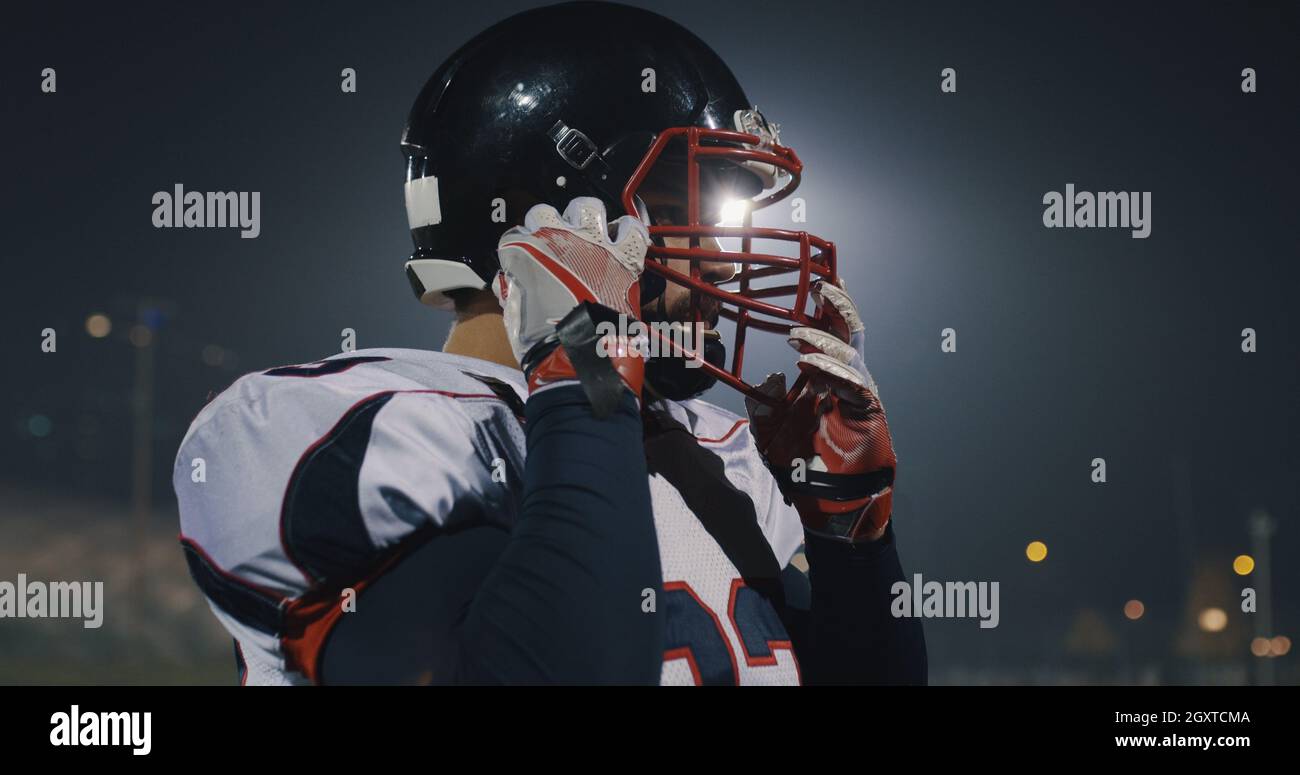 American football player putting on his protective helmet against ...