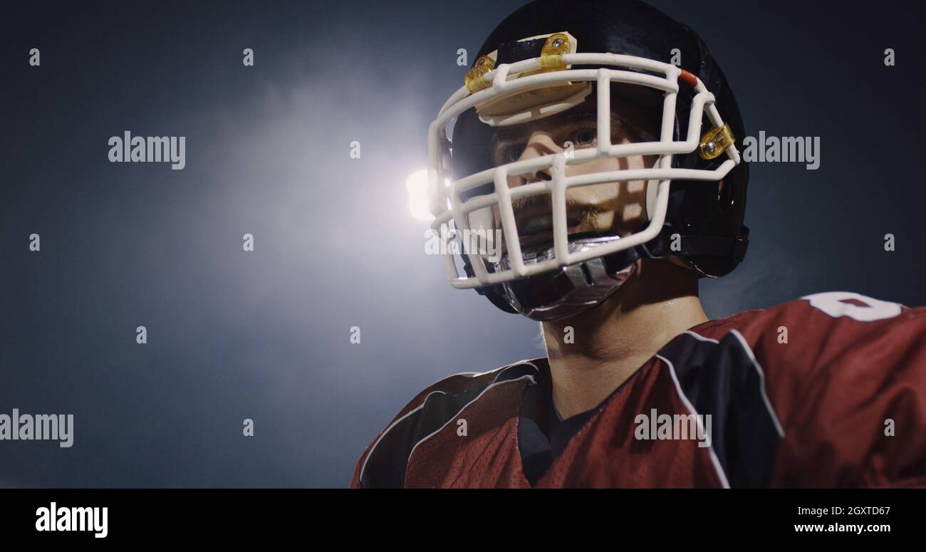 portrait of young confident American football player standing on field ...