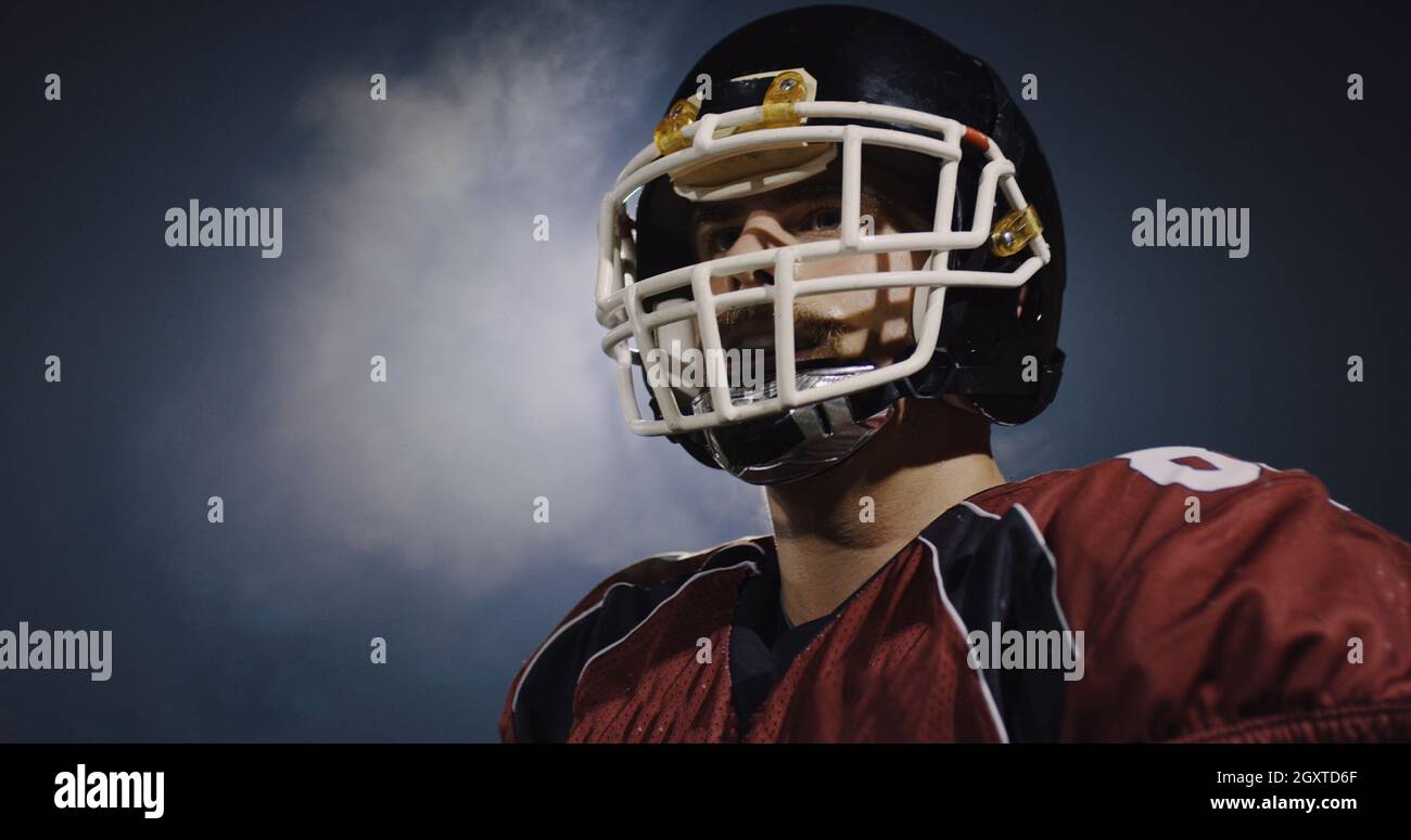 portrait of young confident American football player standing on field ...