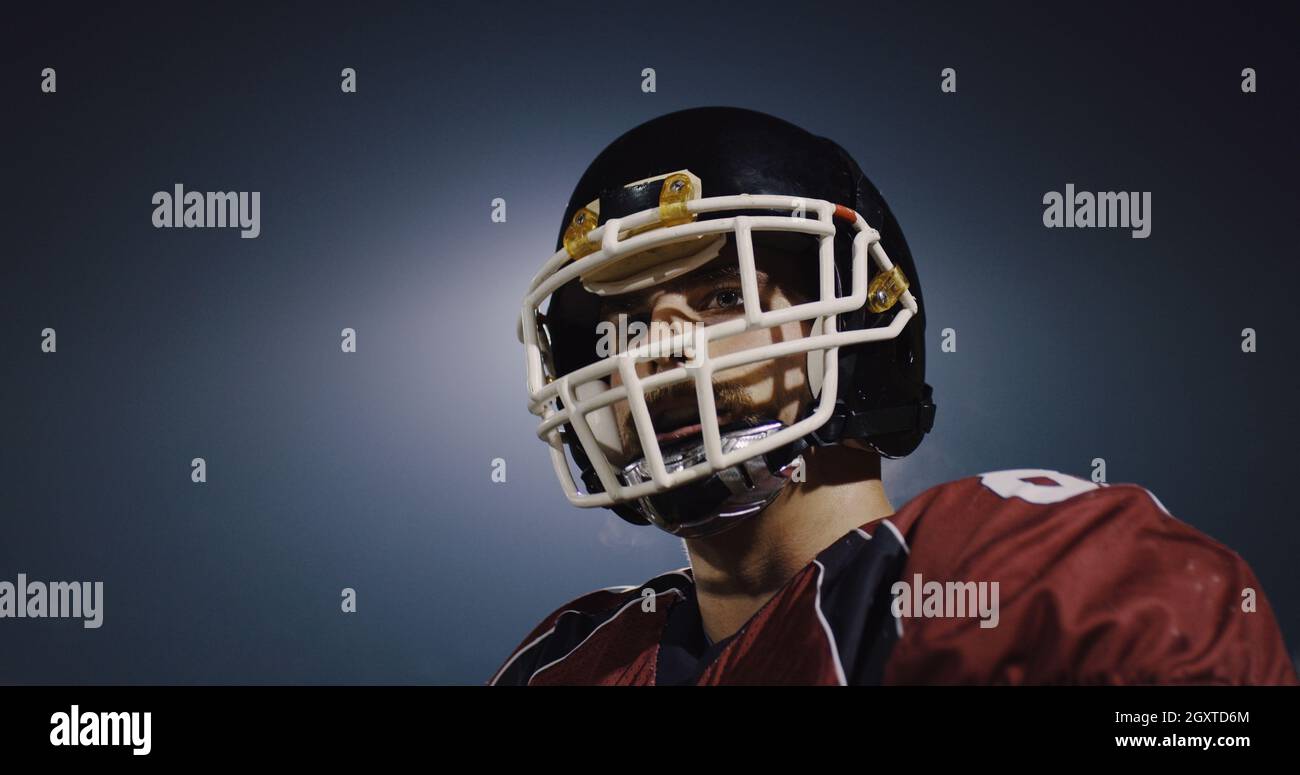 portrait of young confident American football player standing on field ...