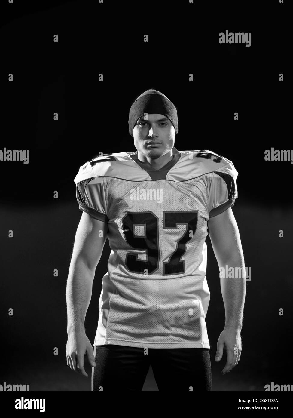 portrait of young confident American football player on field at night ...