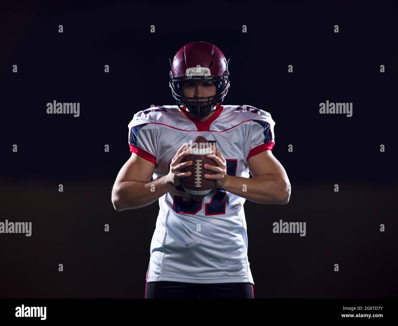 portrait of confident American football player holding ball while ...