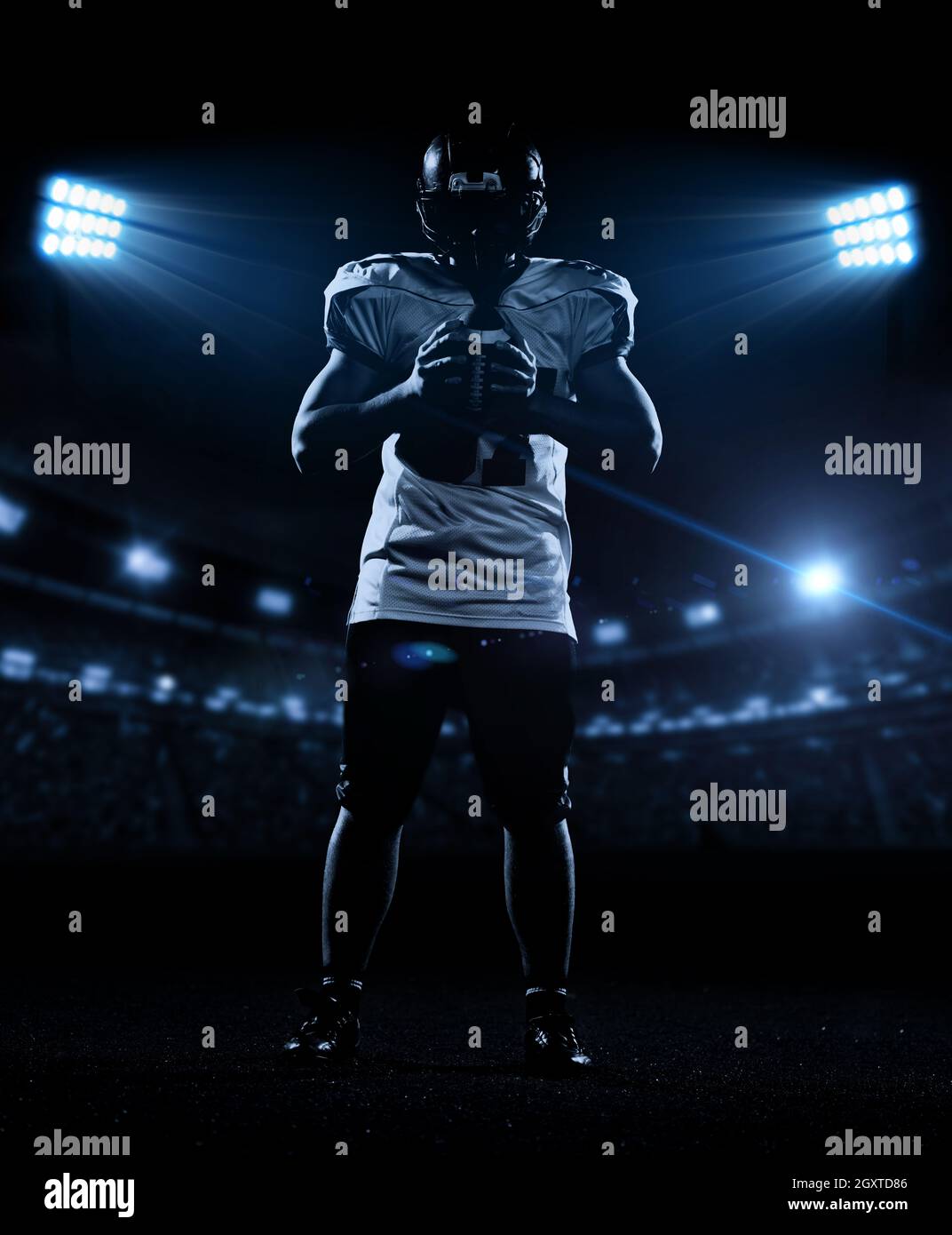portrait of confident American football player holding ball while ...