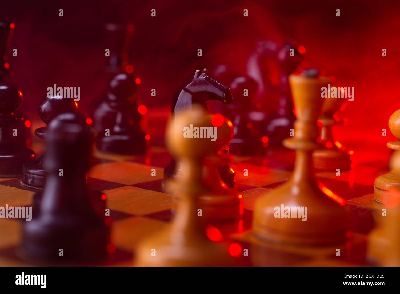 Chess fight, chess pieces on the board, toned in red. Battle fire and ...